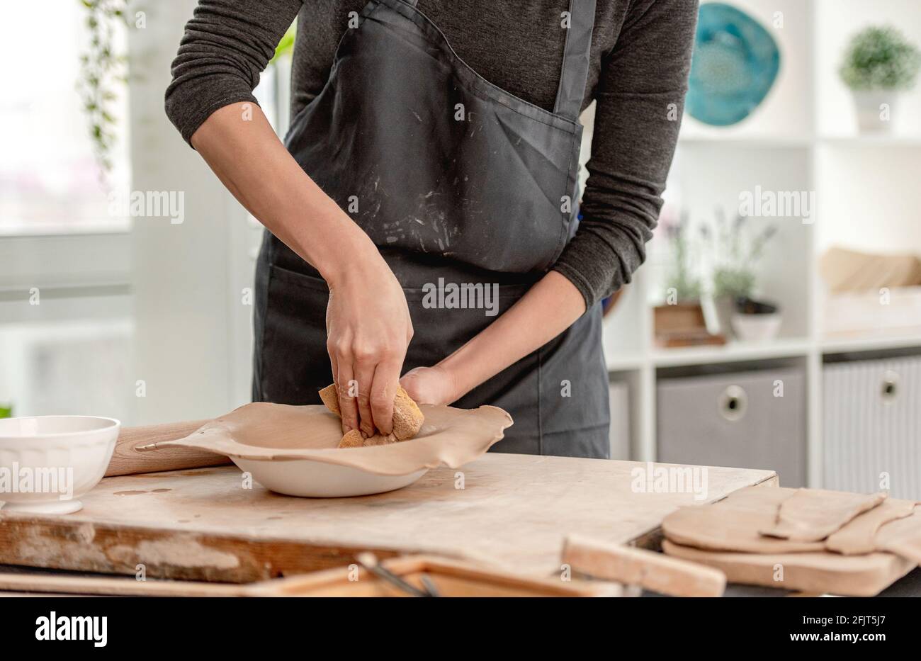 Woman using wet sponge for plate forming Stock Photo - Alamy