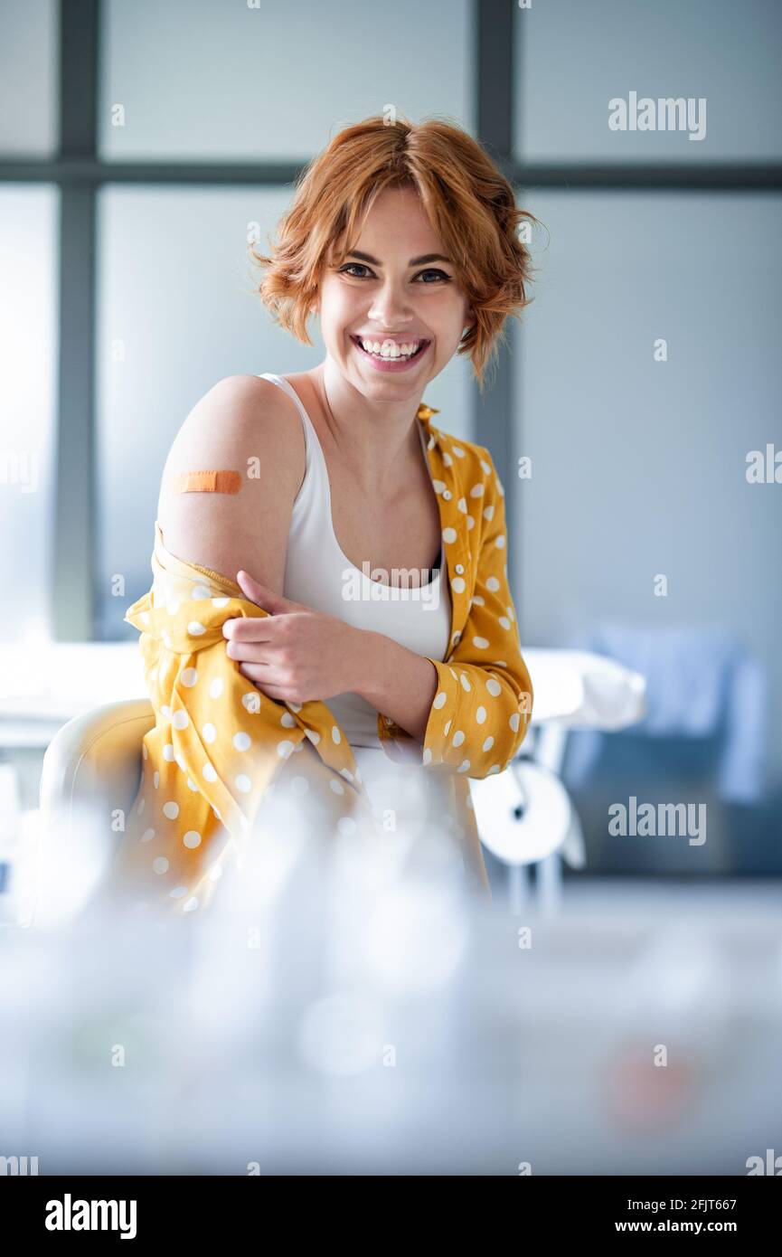 Happy woman with plaster on arm after vaccination in hospital, looking ...
