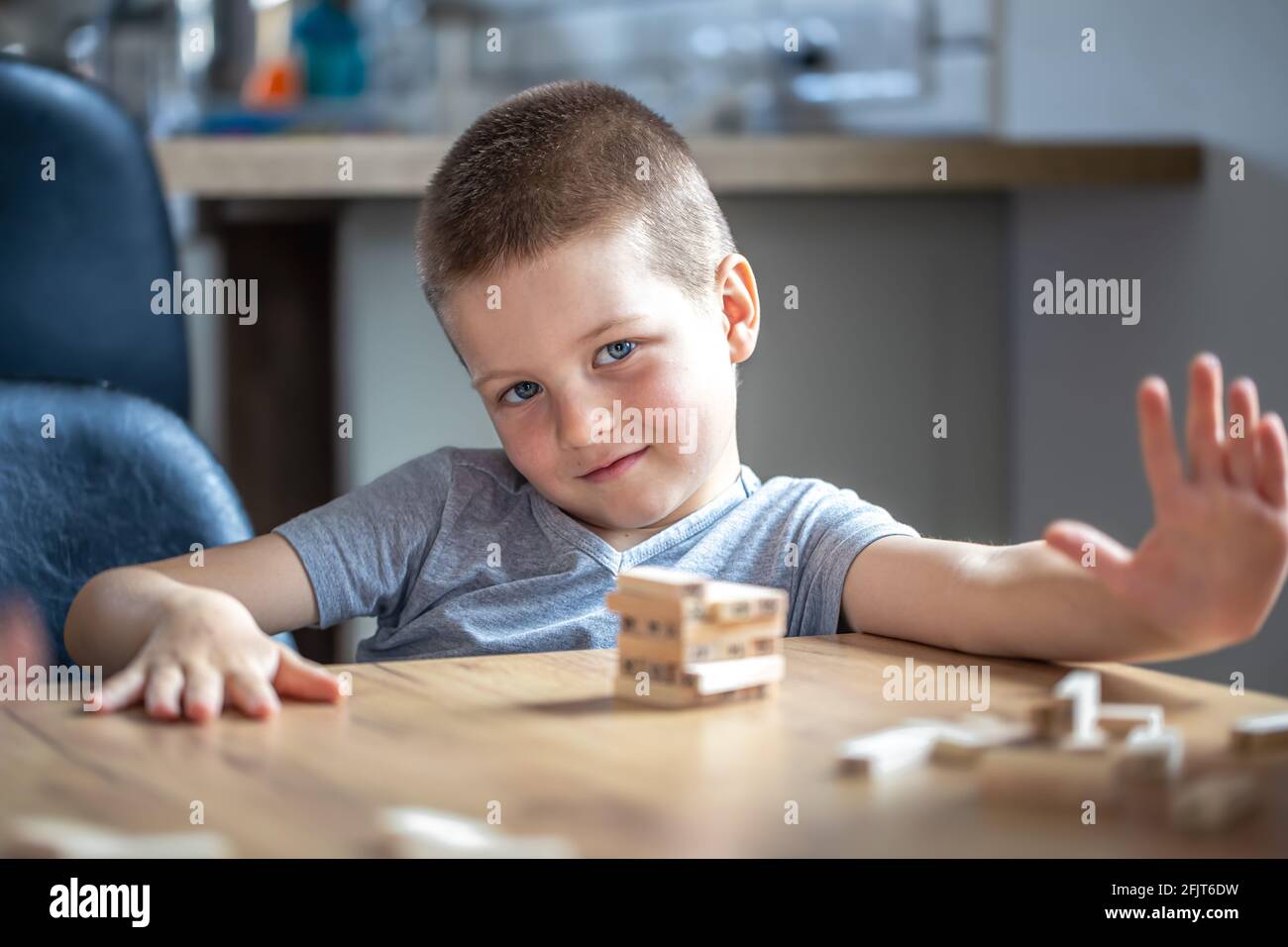 A cute little boy is playing a board game with wooden cubes and a ...