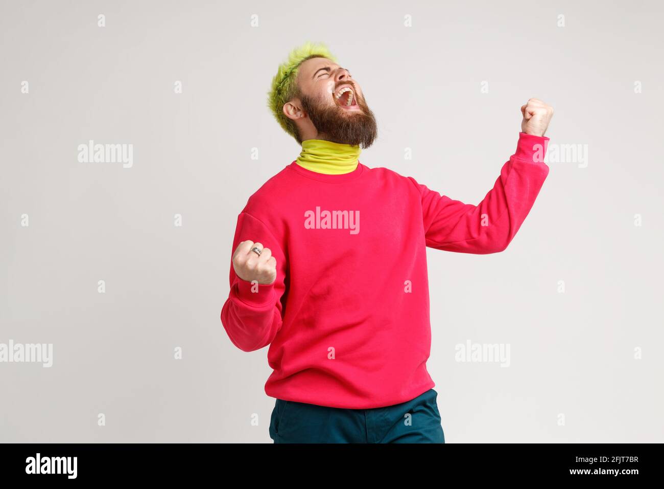 Portrait of cheerful bearded man with excited expression, raising fists ...
