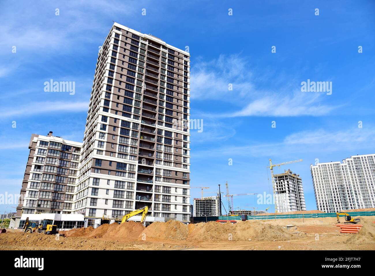 Tower cranes in action on blue sky background. Excavator dig ground for ...