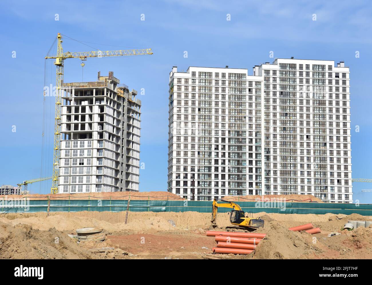 Tower cranes in action on blue sky background. Excavator dig ground for ...