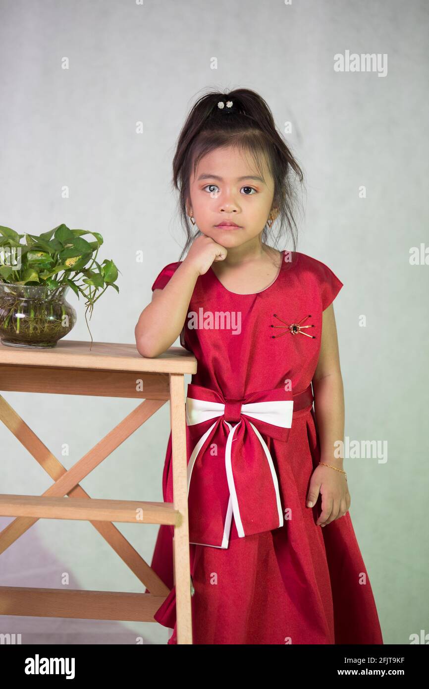 Innocent lovely child dressed in red, posing for a portrait in studio ...
