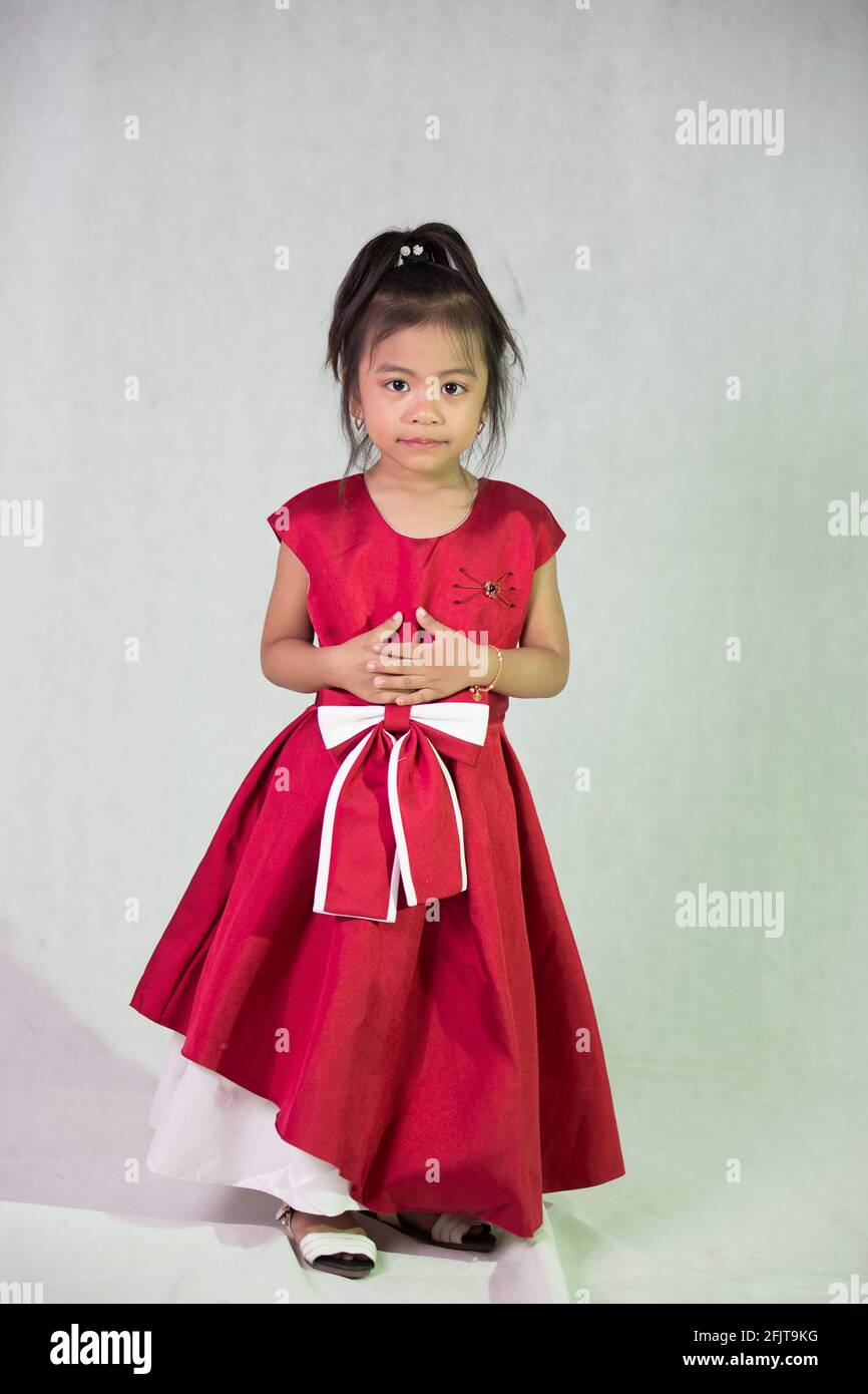 Innocent lovely child dressed in red, posing for a portrait in studio ...