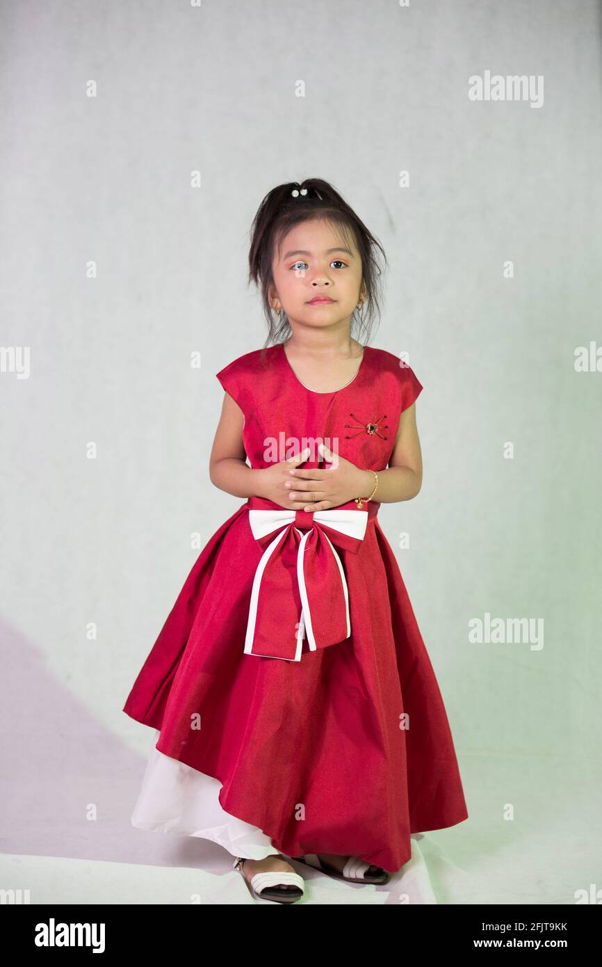 Innocent lovely child dressed in red, posing for a portrait in studio ...