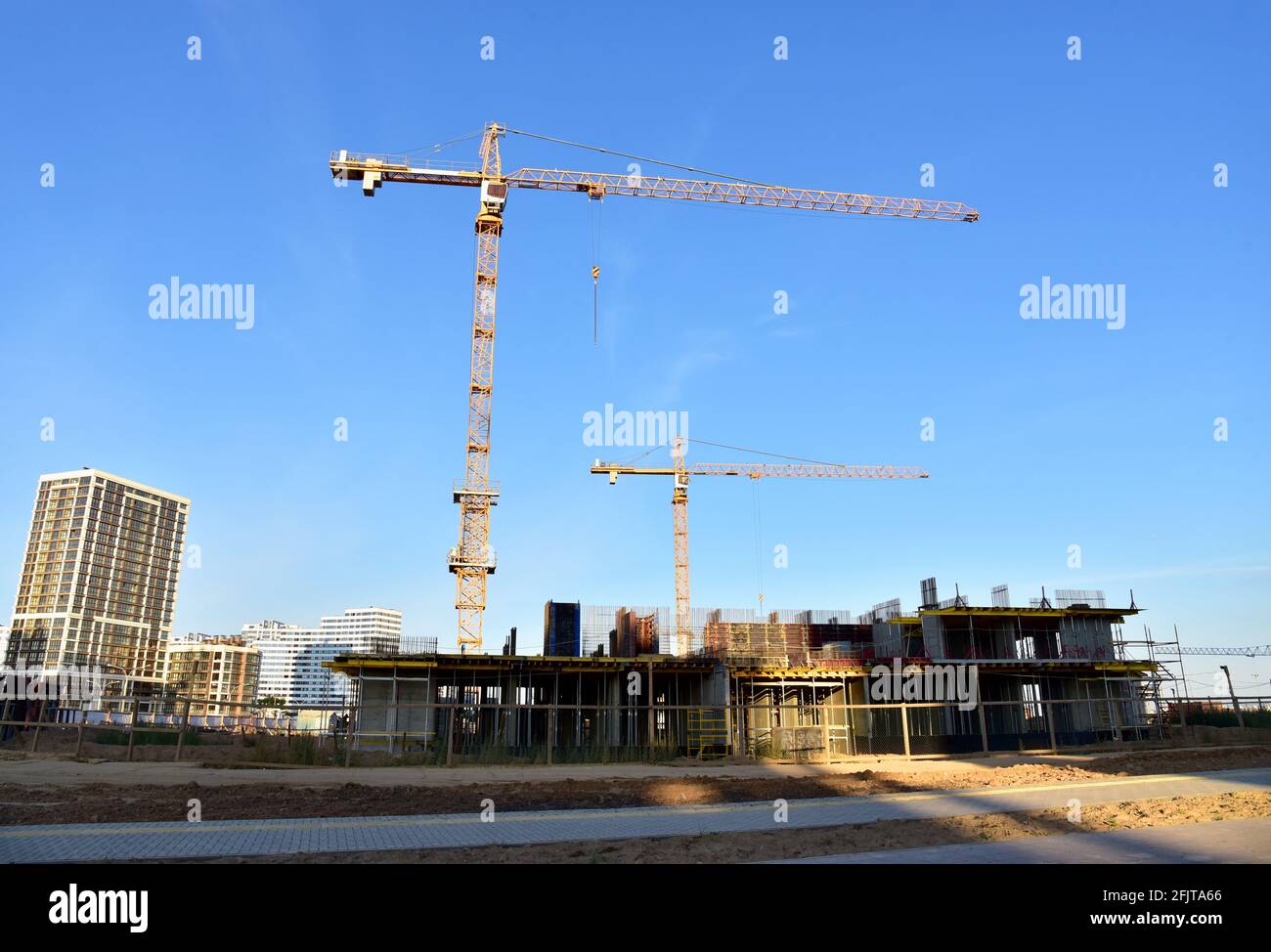 Tower cranes working at construction site on blue sky background ...