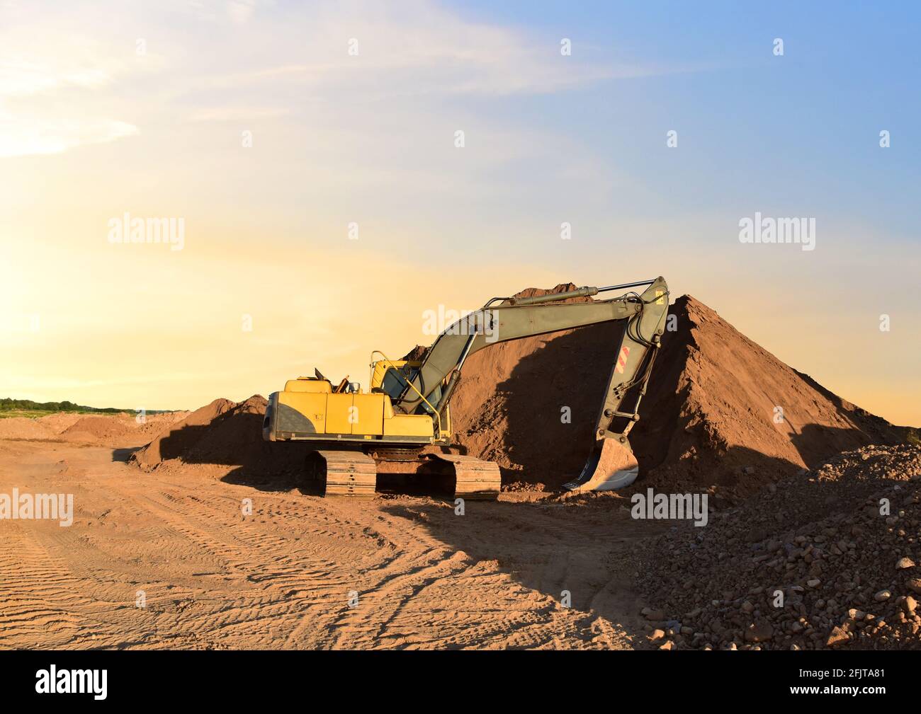 Excavator during earthmoving work at open-pit mining on sunset ...