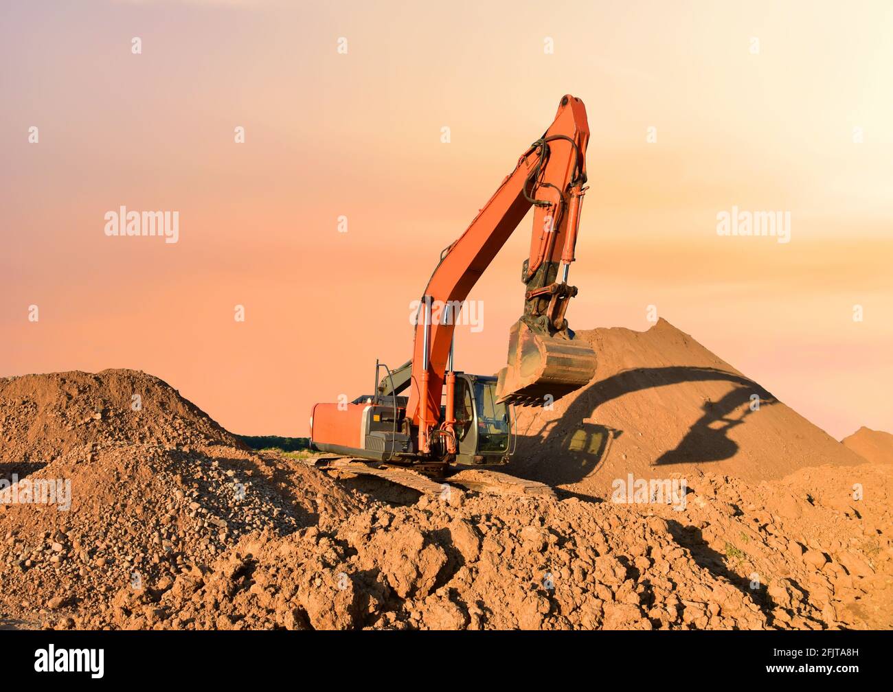 Excavator during earthmoving work at open-pit mining on sunset ...