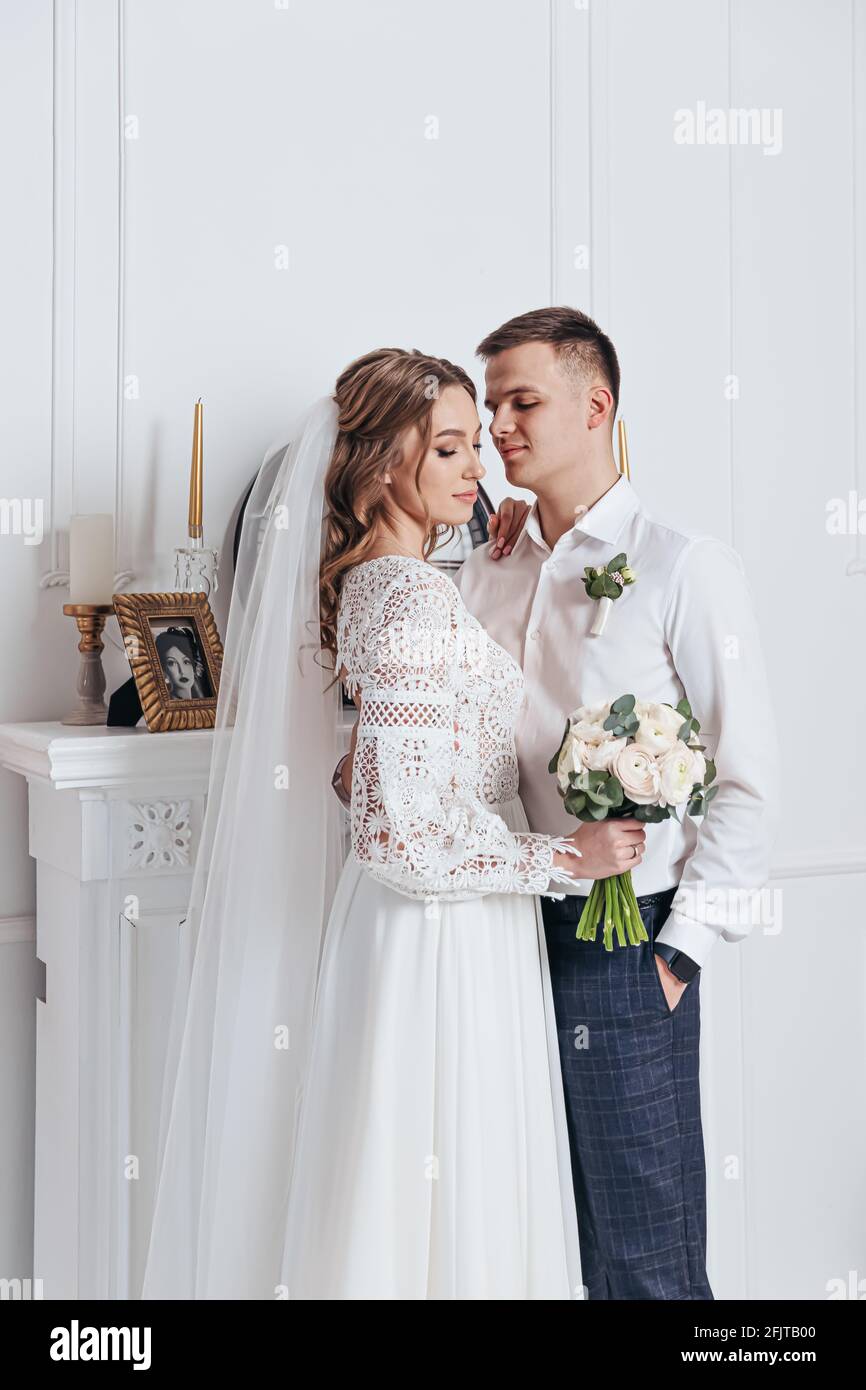 The groom hugs the bride in a boho style lace wedding dress in a cozy ...