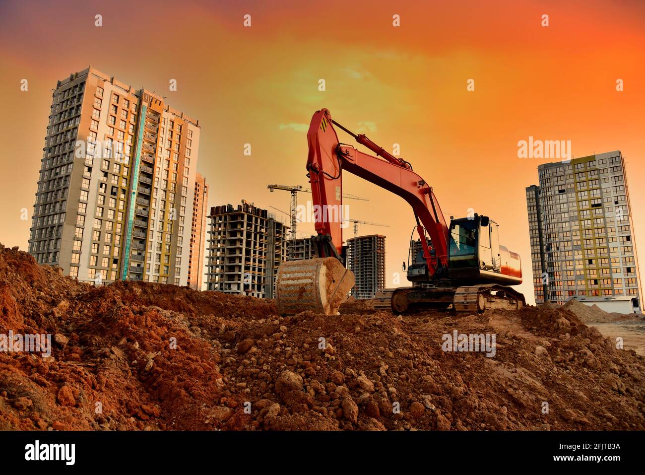 Excavator during earthmoving work at construction site on sunset ...