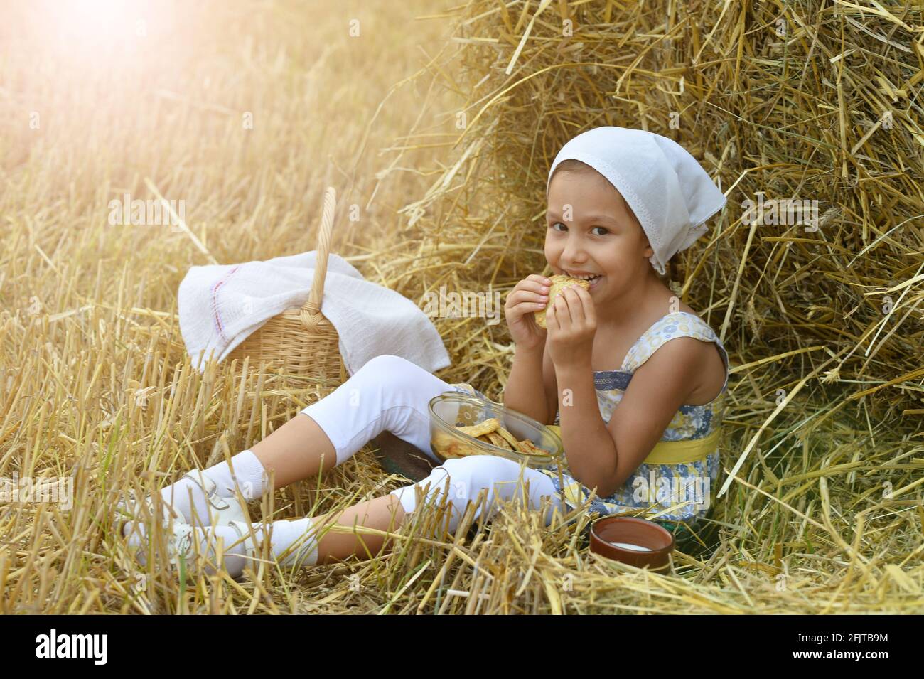 Portrait of little girl eating on a haystack Stock Photo - Alamy