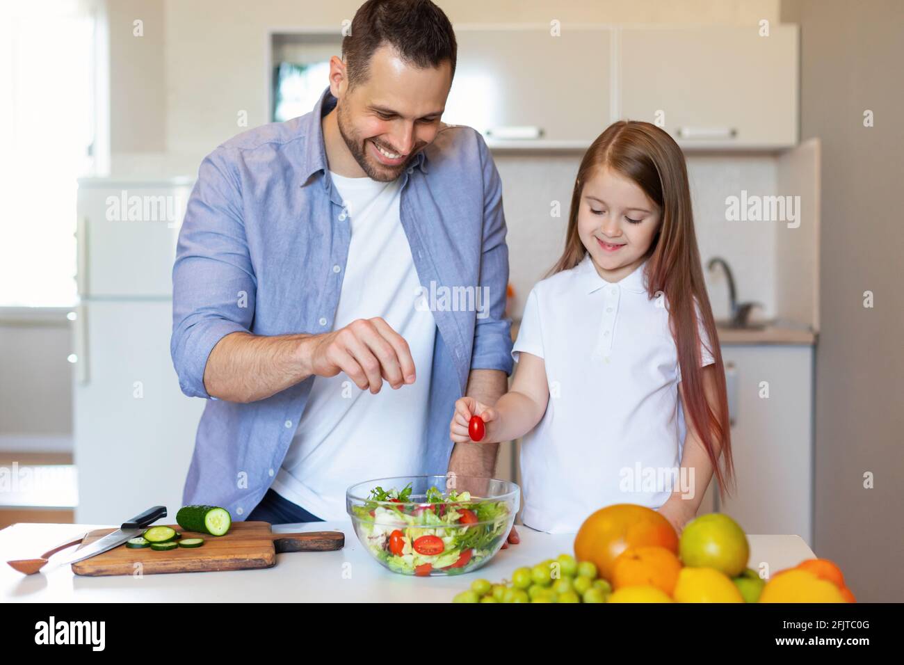 Happy Little Girl Cooking With Daddy Preparing Salad In Kitchen Stock ...