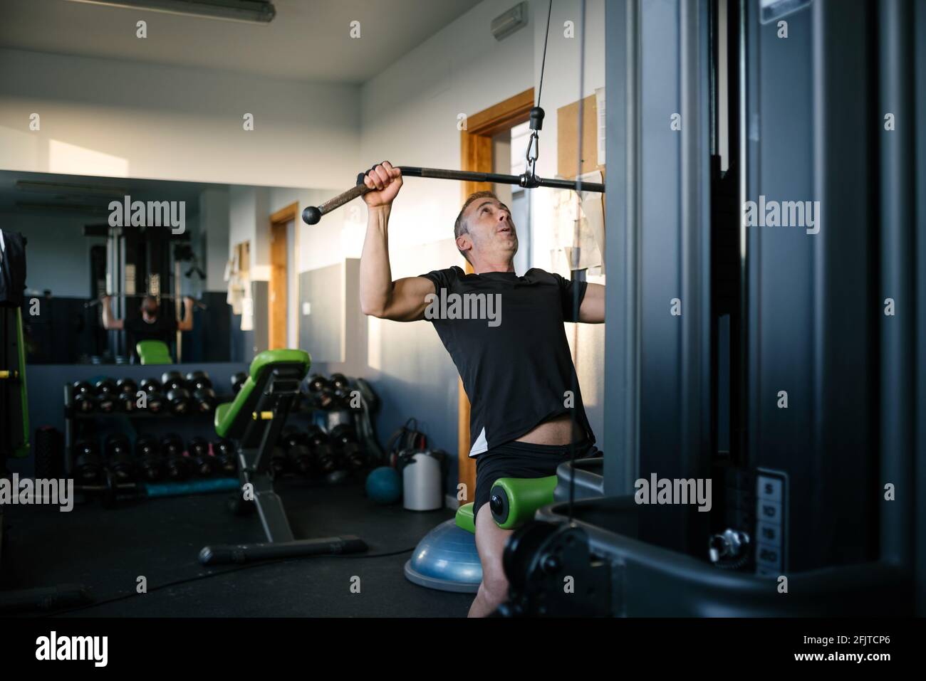 Concept: sport. Athlete man in the gym. Doing pull-ups on the machine ...