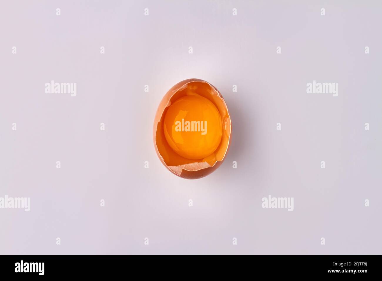 Raw cracked chicken egg with yolk Stock Photo - Alamy