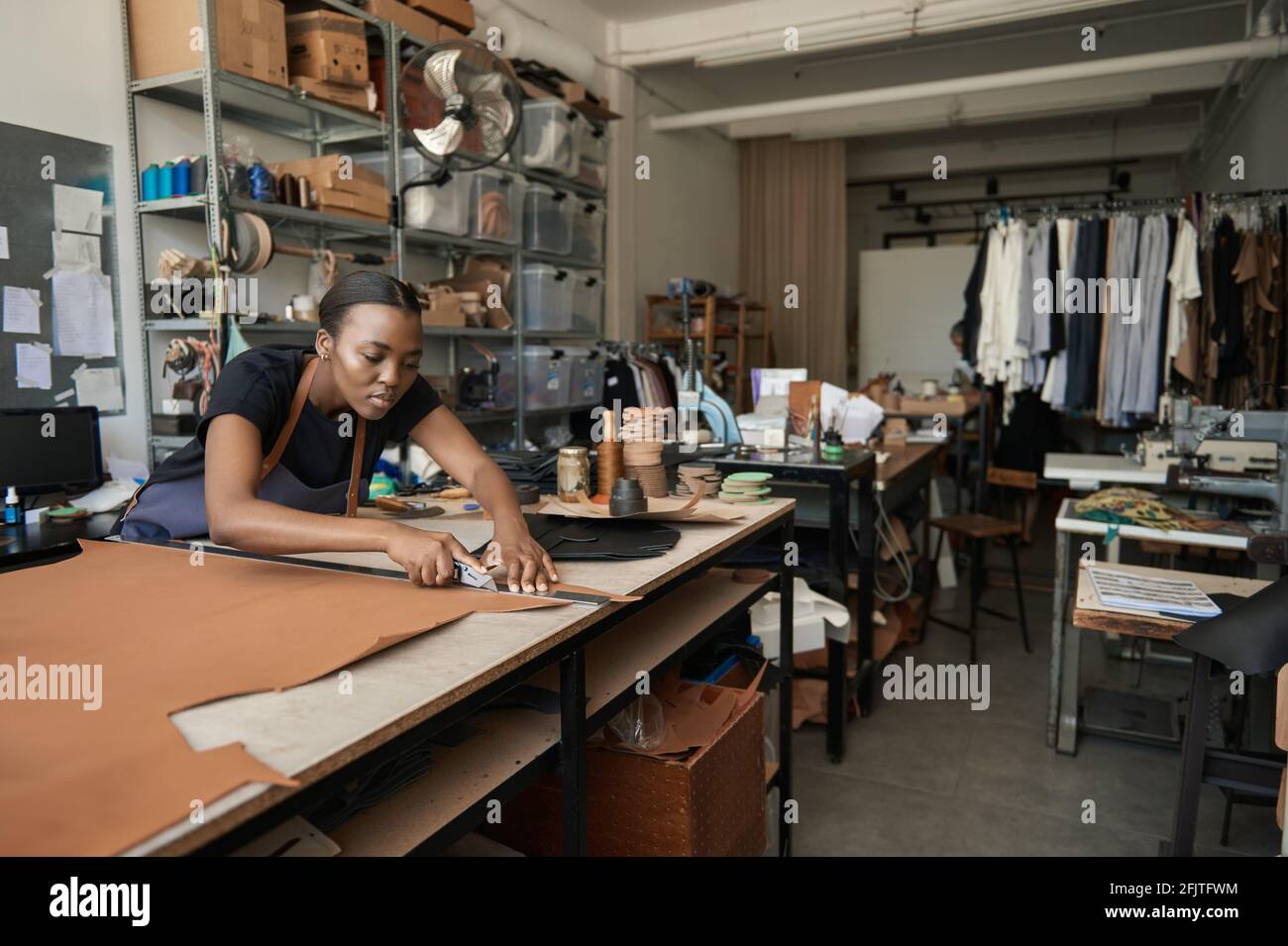 African female artisan cutting leather at a workshop bench Stock Photo ...
