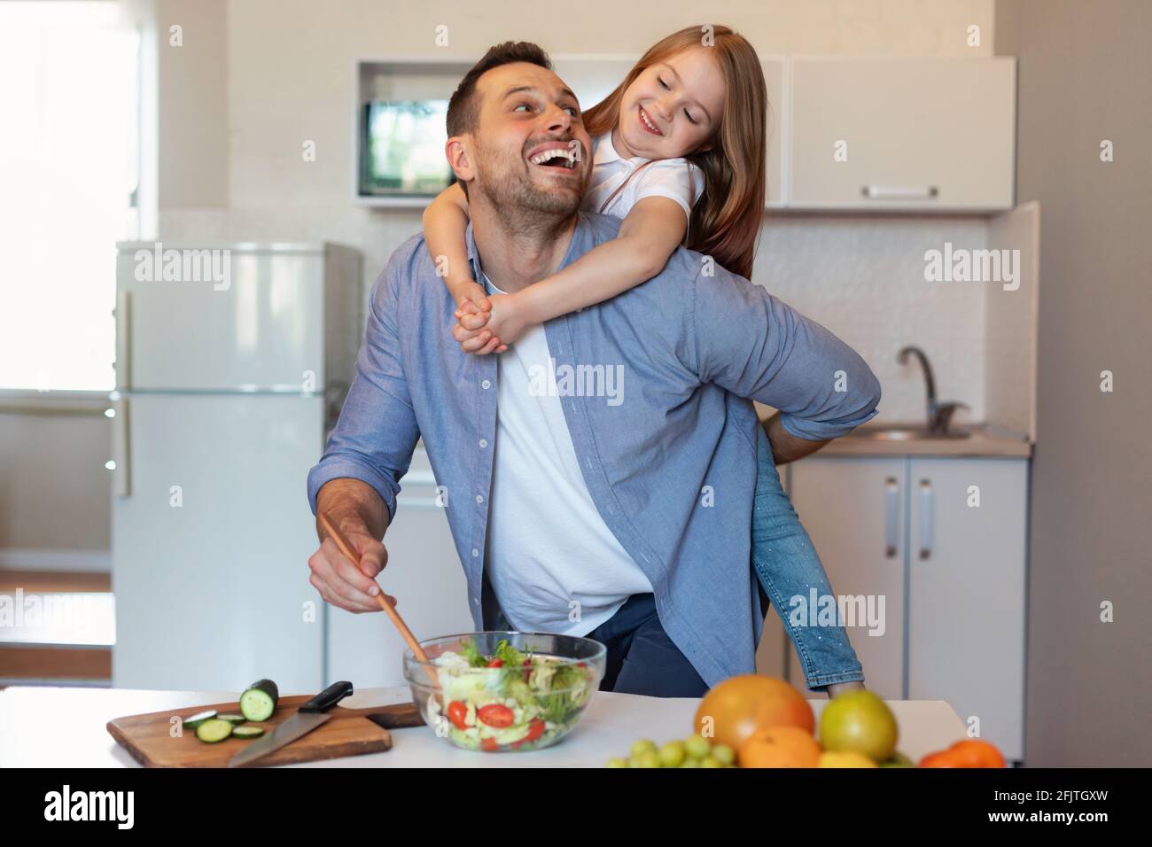 Little Daughter Hugging Daddy While He Cooking In Kitchen Stock Photo ...