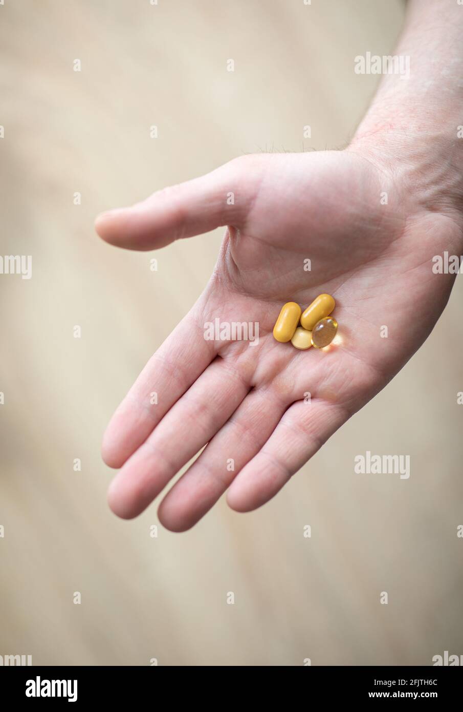 Vitamins and supplements. The man is holding the tablets in his right ...