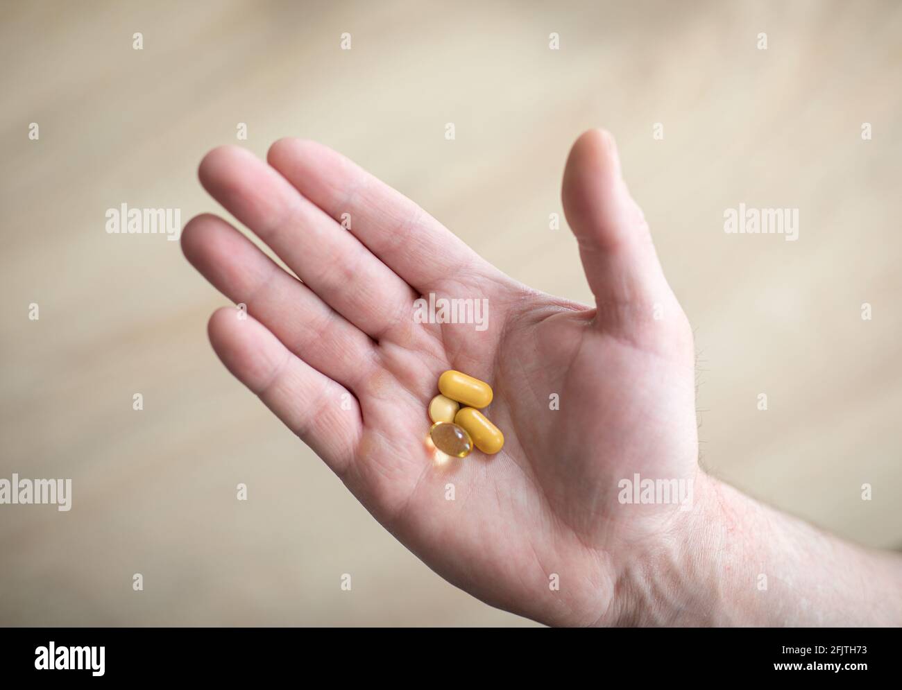 Vitamins and supplements. The man is holding the tablets in his right ...