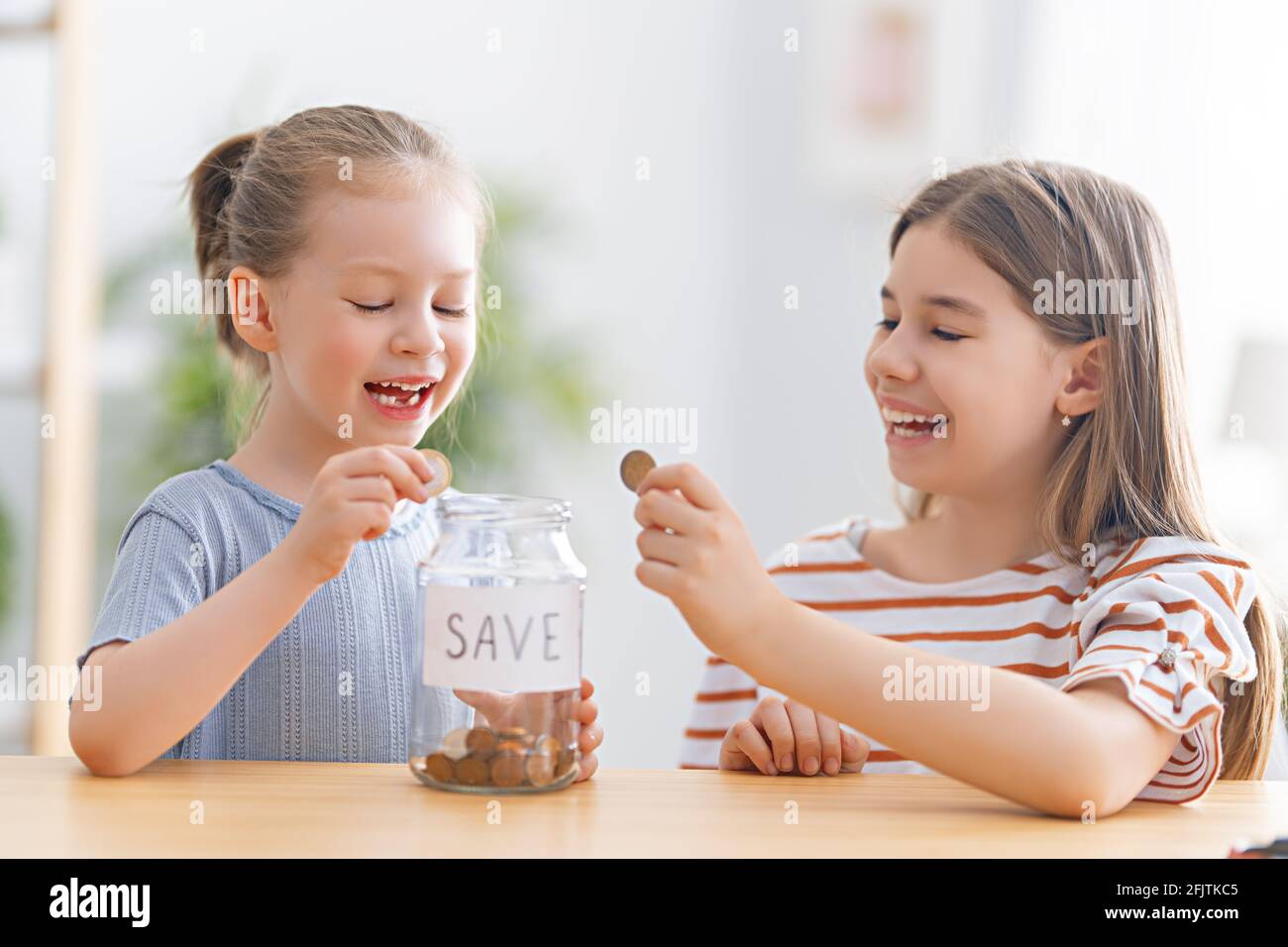 Happy girls with coin box. Children are smiling Stock Photo - Alamy