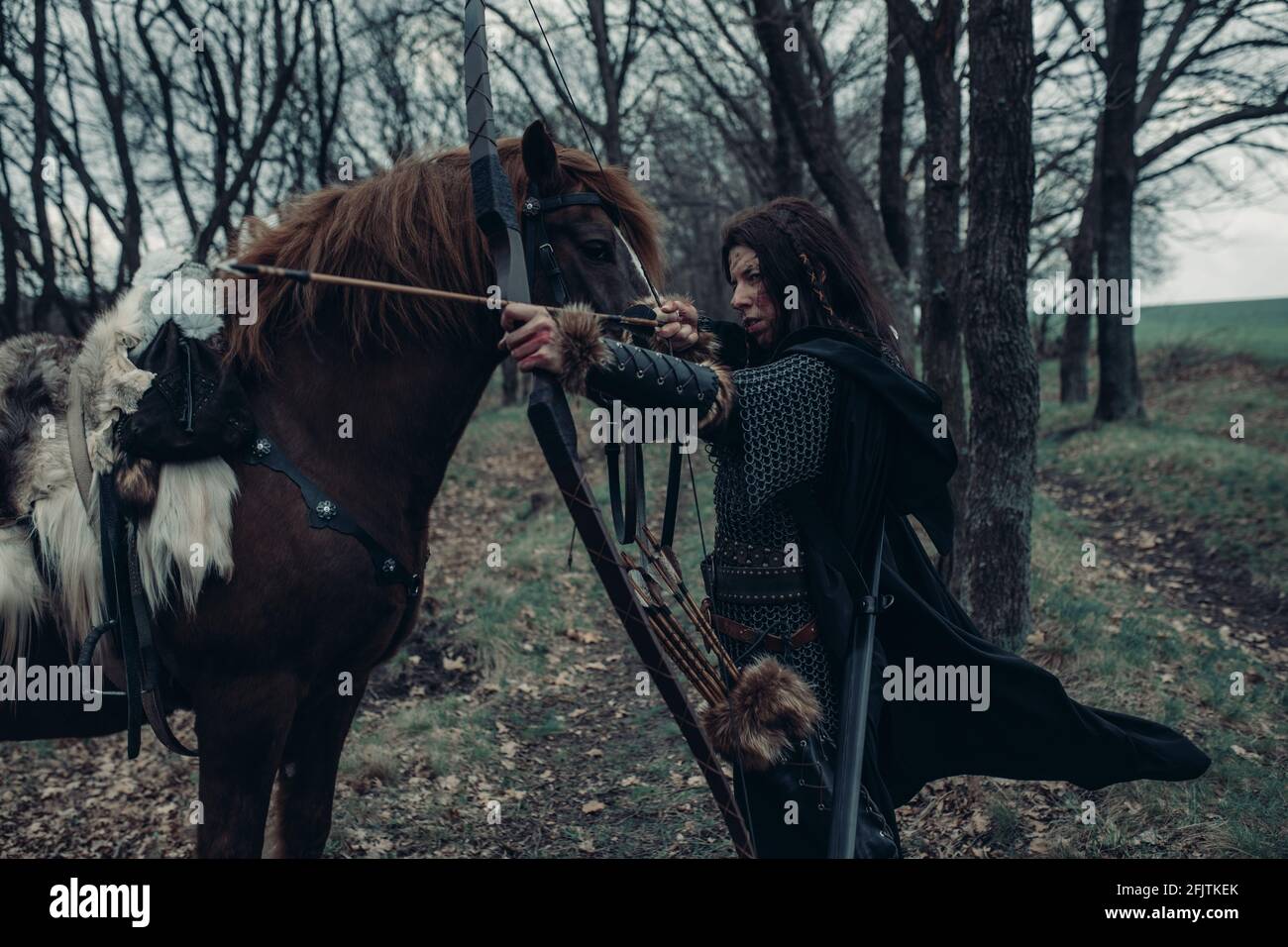 Woman in image of medieval warrior archer shoots a bow and aims at ...