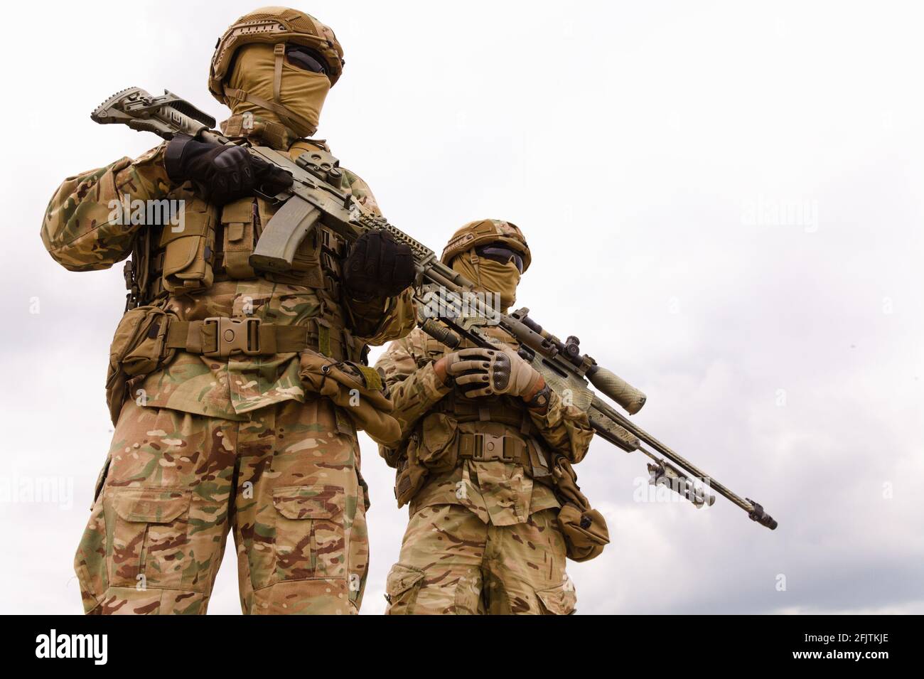 Two special forces soldiers with rifles against sky background, space ...