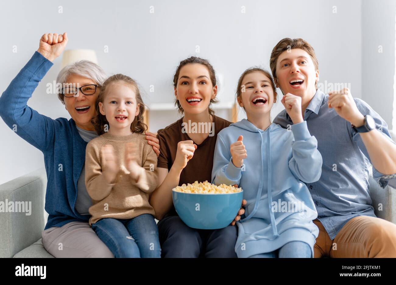 Happy family watching projector, TV, movies with popcorn at home ...