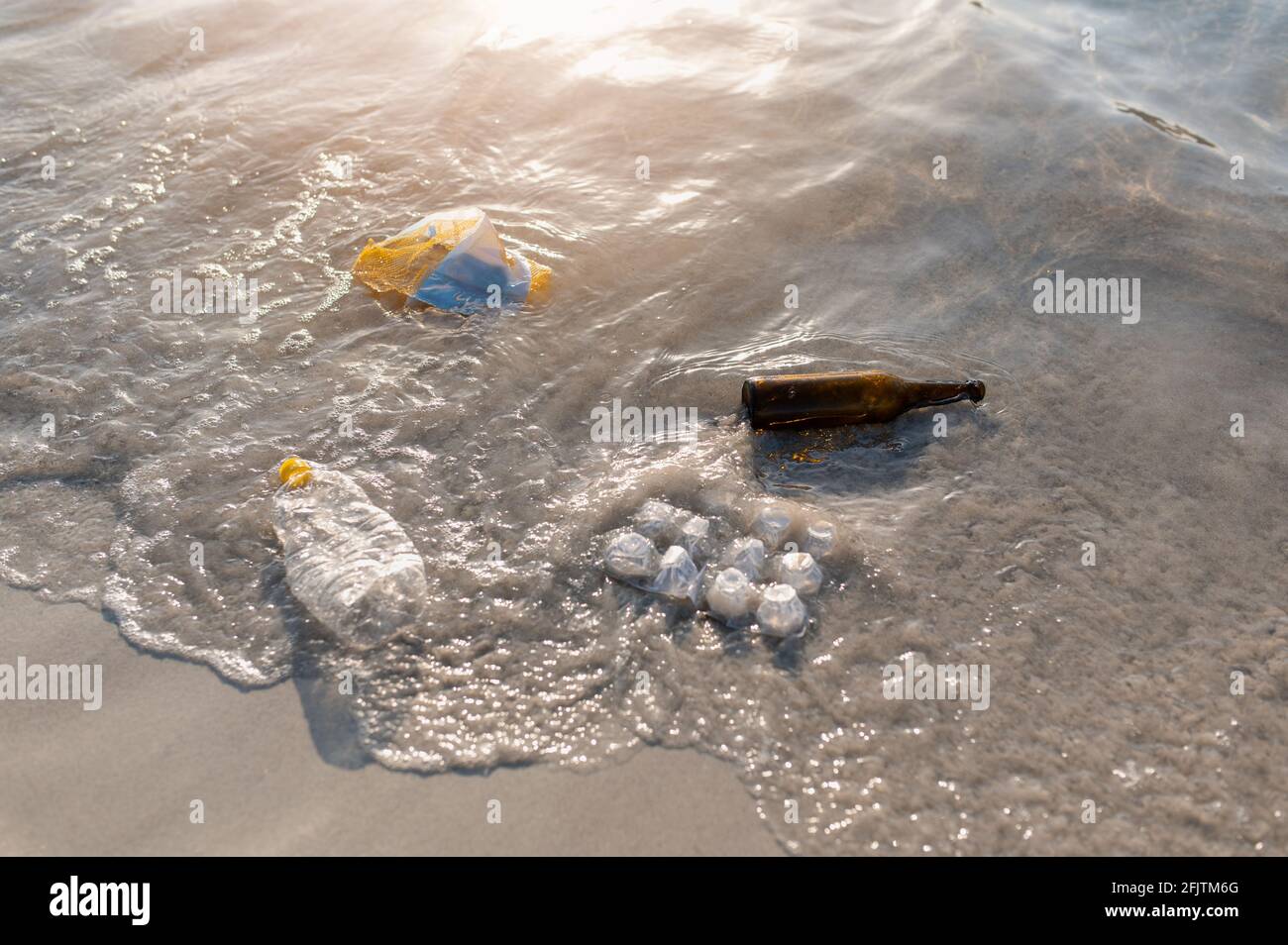 Waste floating on the sea water in the shore. Empty bottles and plastic ...