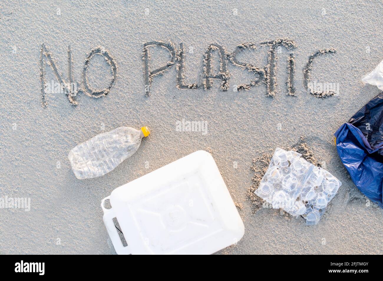 No plastic written on the sand framed by waste and garbage. Ecological ...