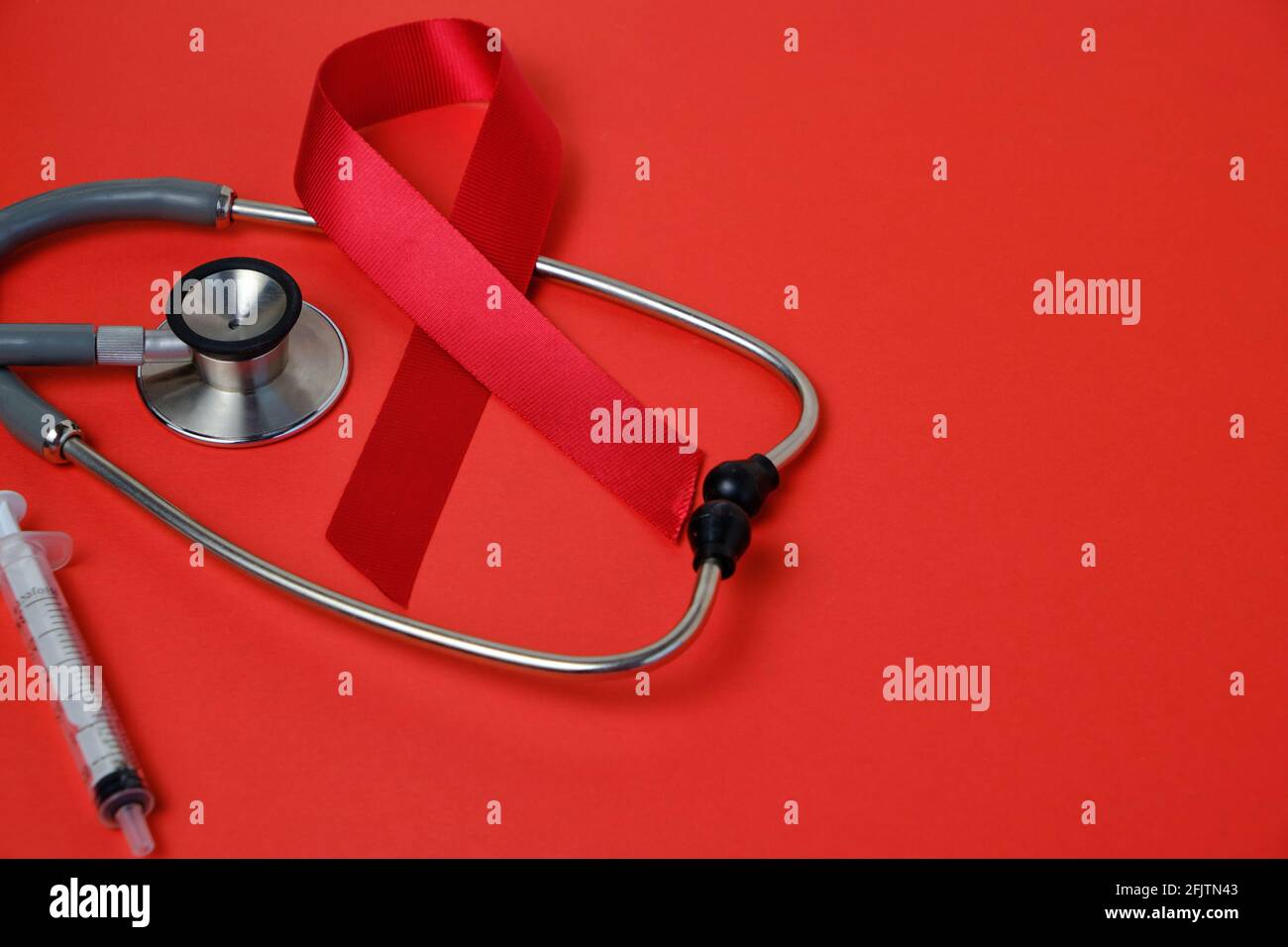 Red ribbon is symbol of AIDS, drug addiction problems, stethoscope and ...