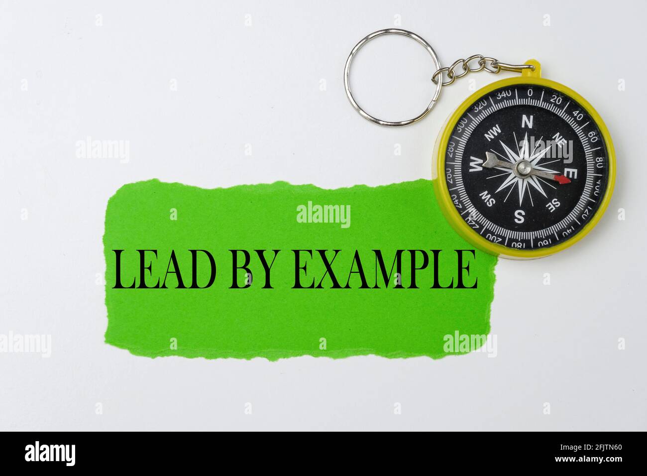 Lead by example written on a green torn paper with compass Stock Photo ...