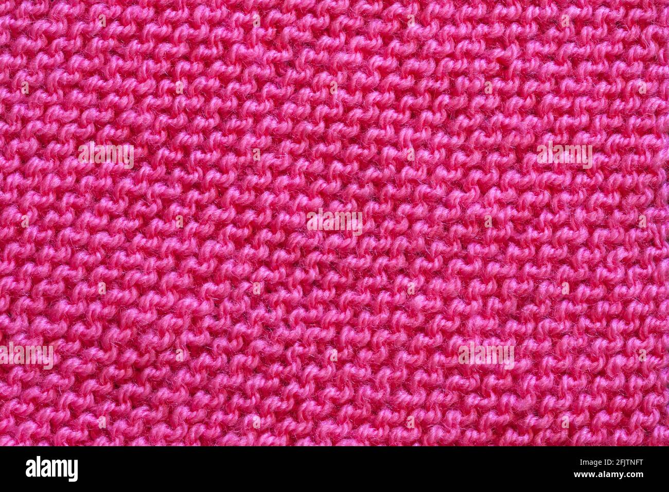 close up detail of pink knitted square for sewing together to make a ...