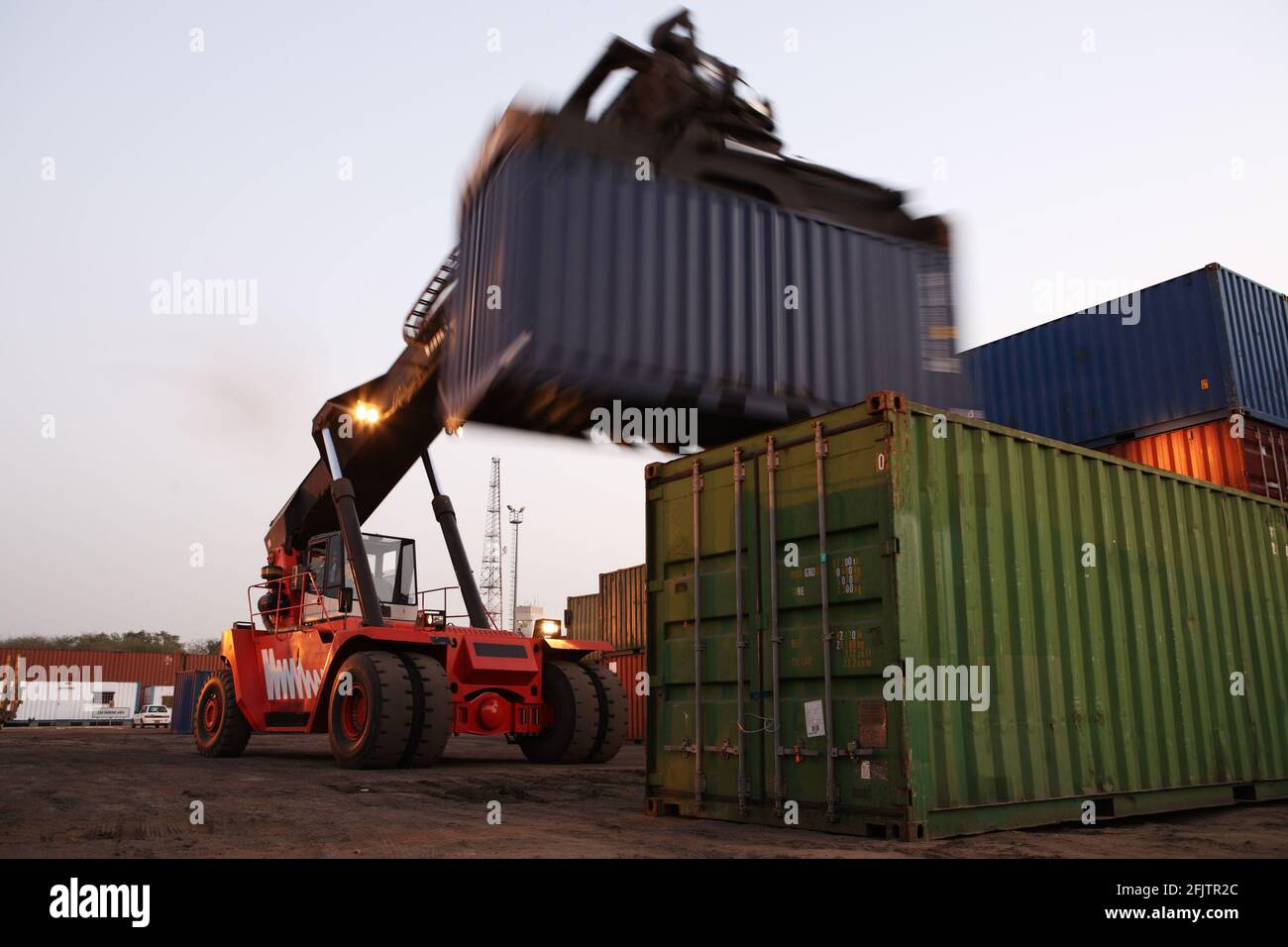 Forklift lifting and stacking cargo containers in a dockyard during ...