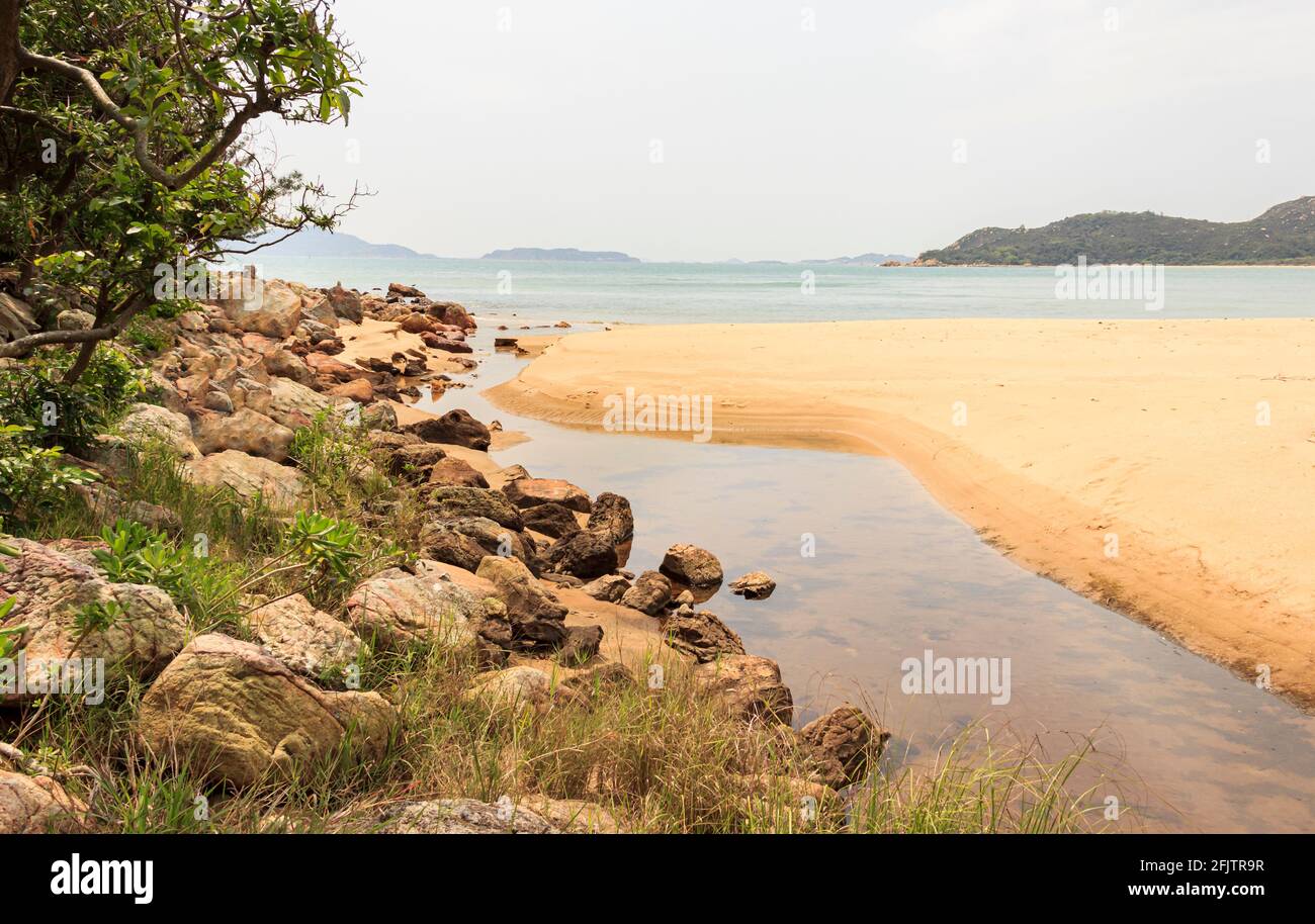 A small waterway, which separates small sand dune and rocks, ends at ...