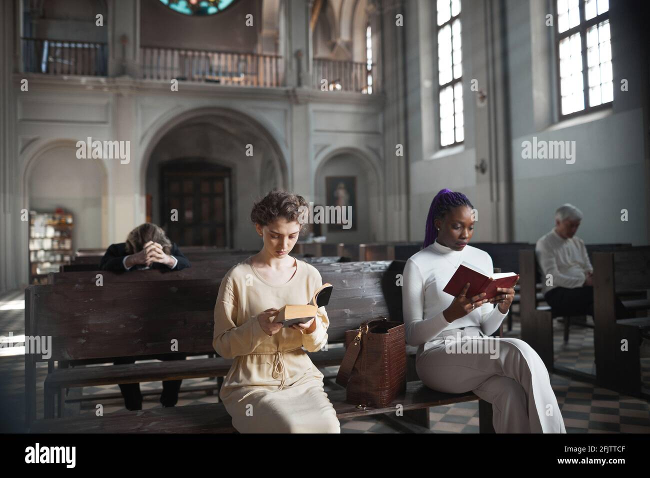 Group of people sitting on the bench reading Bible and praying during ...