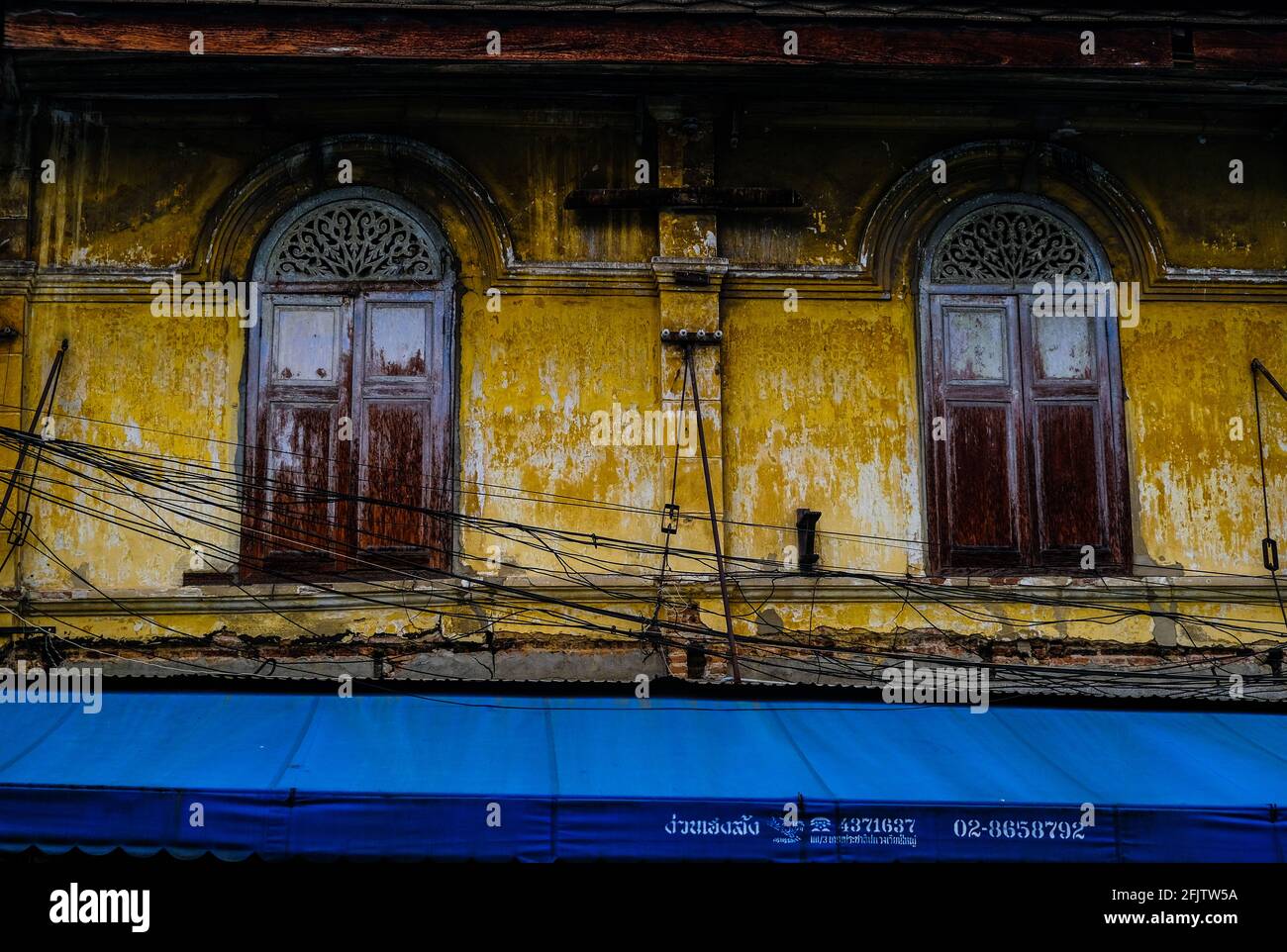 An old yellow colored building facade in the Chinatown area of Bangkok ...