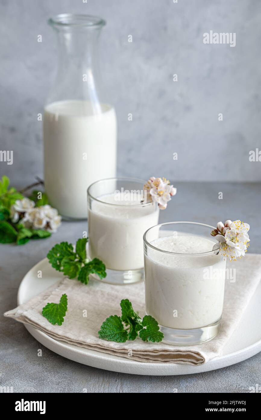 Two glasses of lassi on a gray background with green. A traditional ...