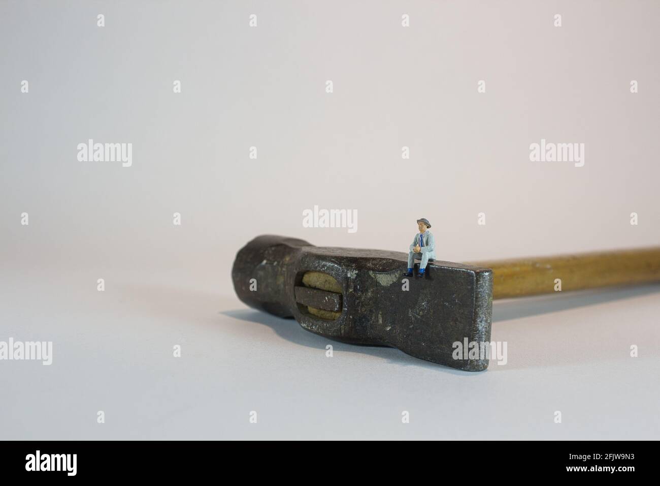 Minifigure of a man sitting on the head of the hammer Stock Photo - Alamy