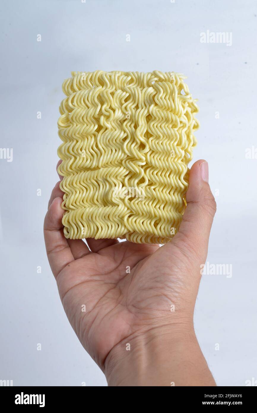 hand holding raw instant noodles, white background Stock Photo - Alamy