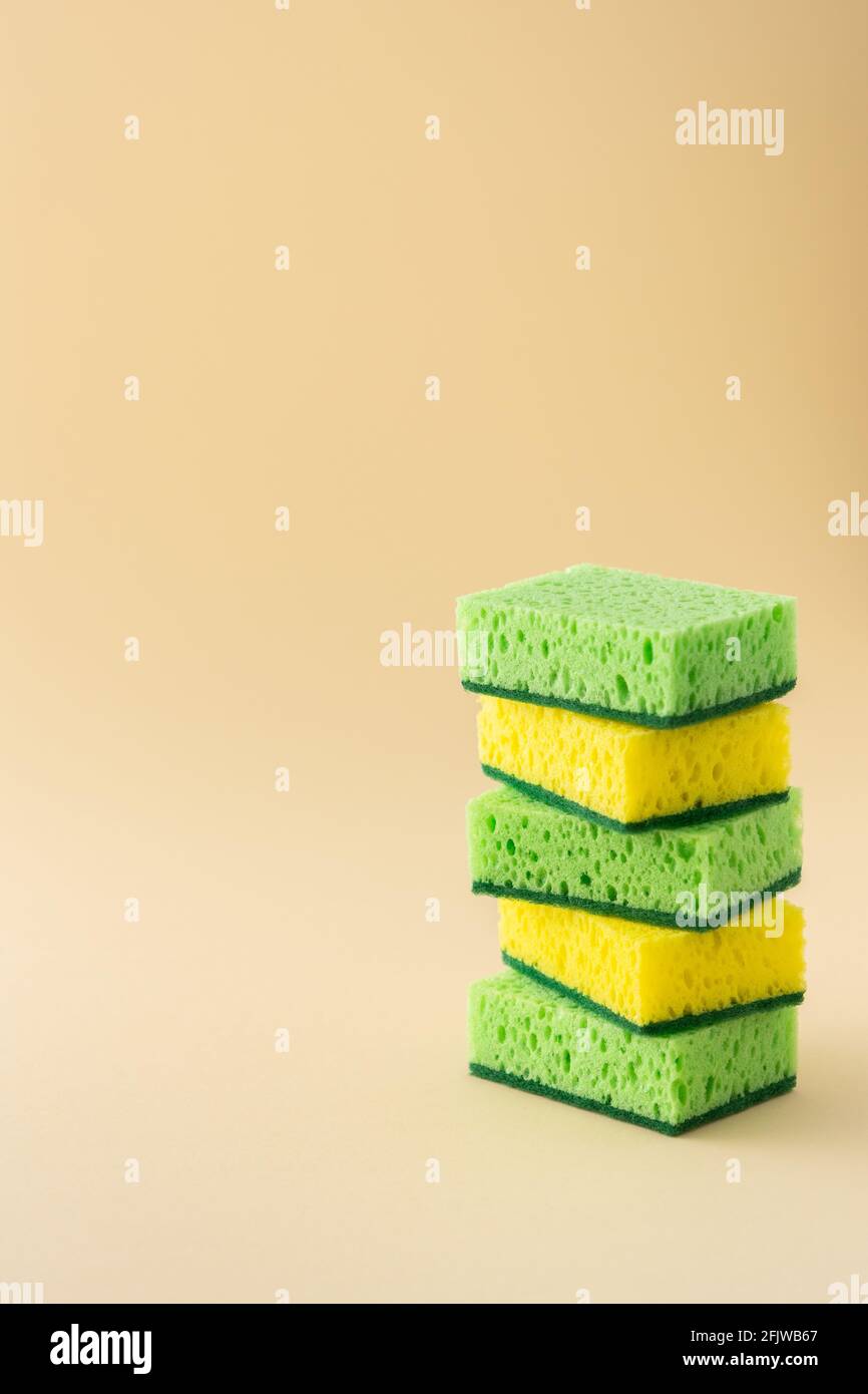 Stack of green and yellow dishwashing sponges on neutral beige ...
