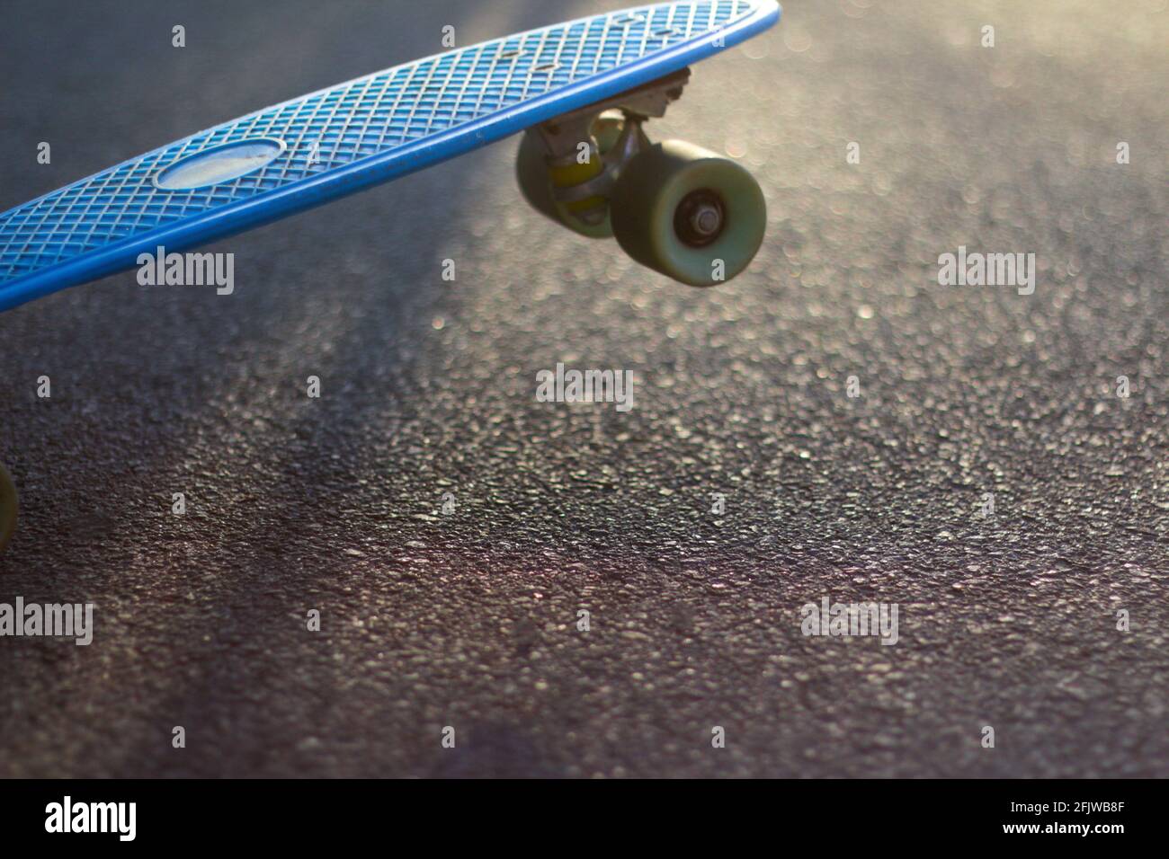 Defocus close-up blue penny board on the asphalt road in the sunshine ...