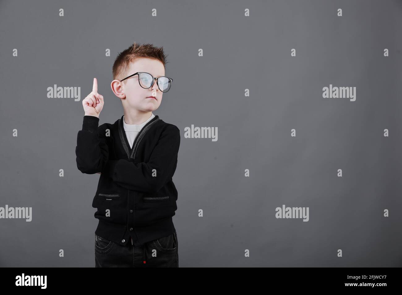 Portrait of stylish little boy with finger pointed up. Little child in ...
