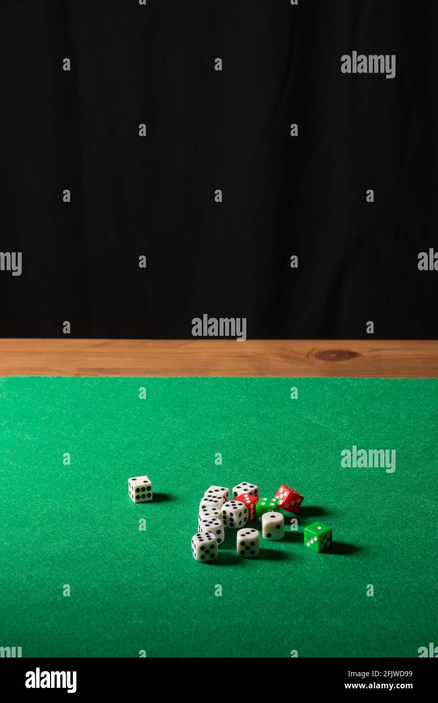 View of green baize with white, green and red dice on wooden table and ...