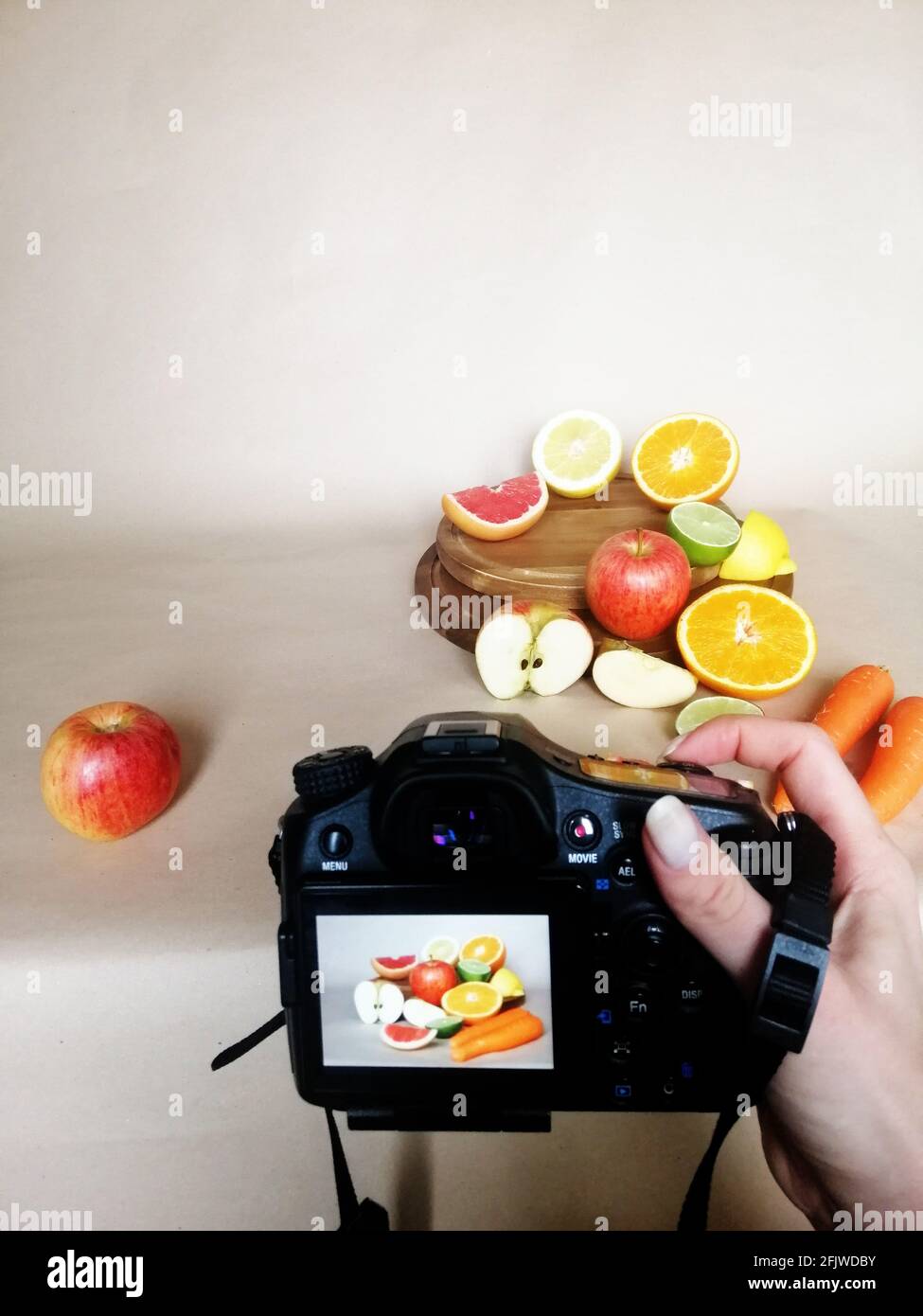 Vertical shot of fruits and a camera in a studio on a white background ...
