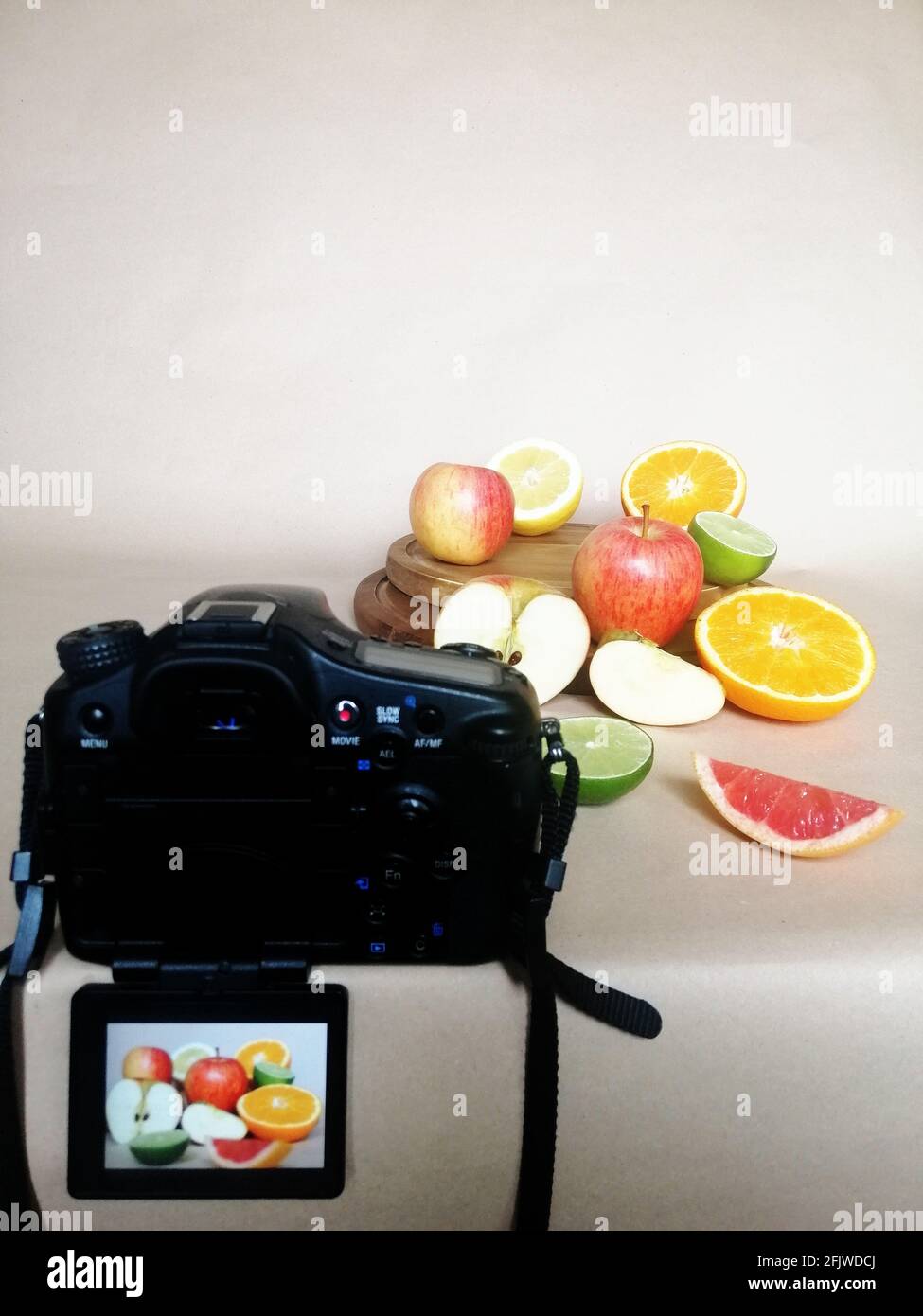 Vertical shot of fruits and a camera in a studio on a white background ...
