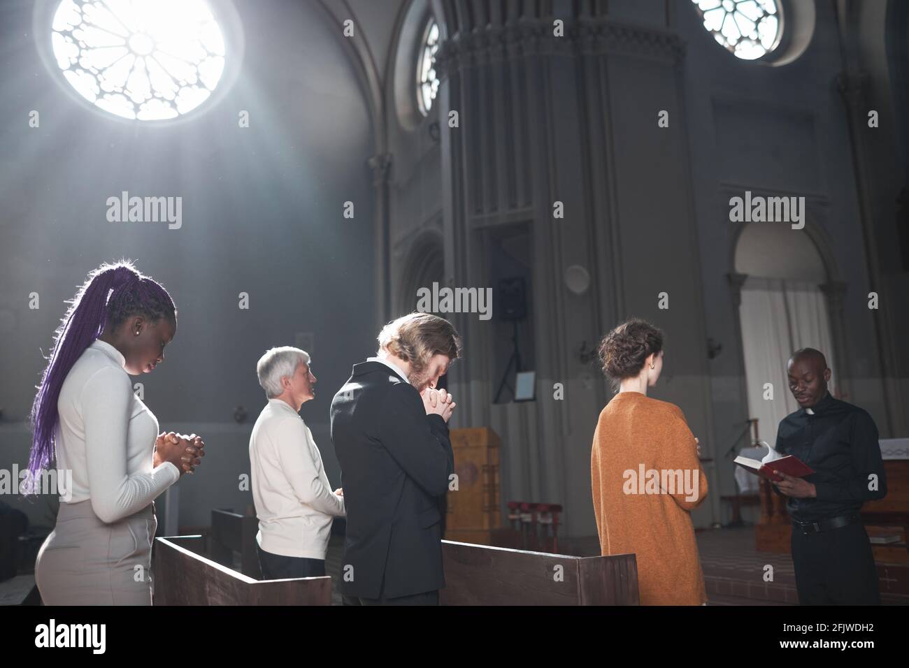 Group of people standing in the church during a mass with priest Stock ...