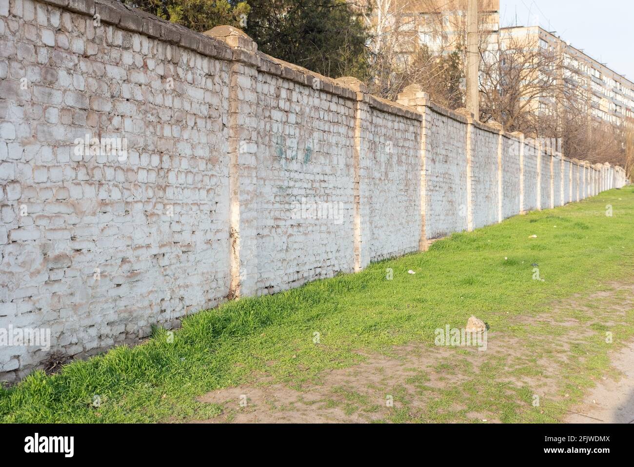 street old white brick fence with grass. Copy space texture green hedge ...