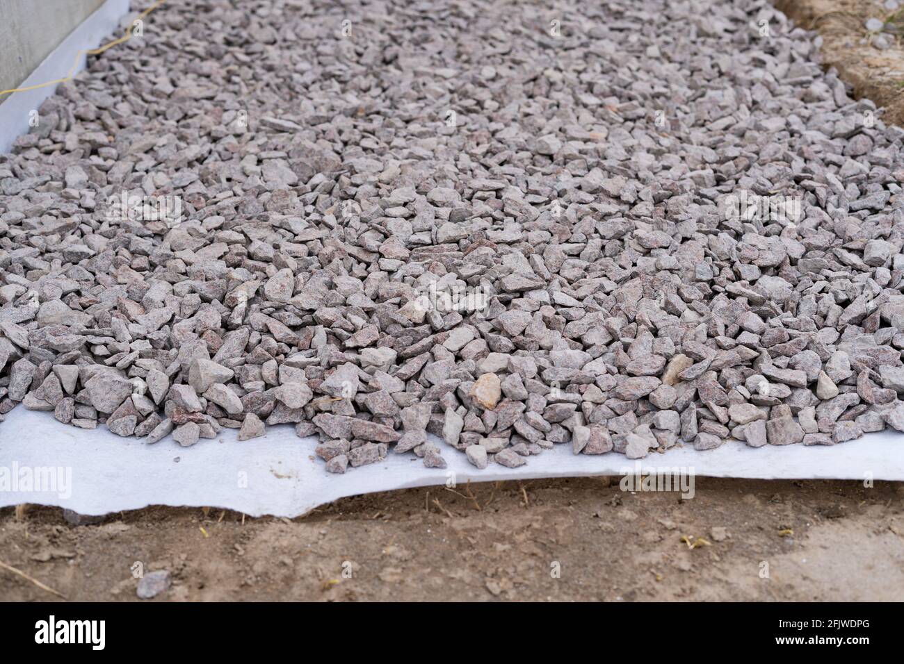 Construction crushed stone is poured and compacted on agrofibre before ...