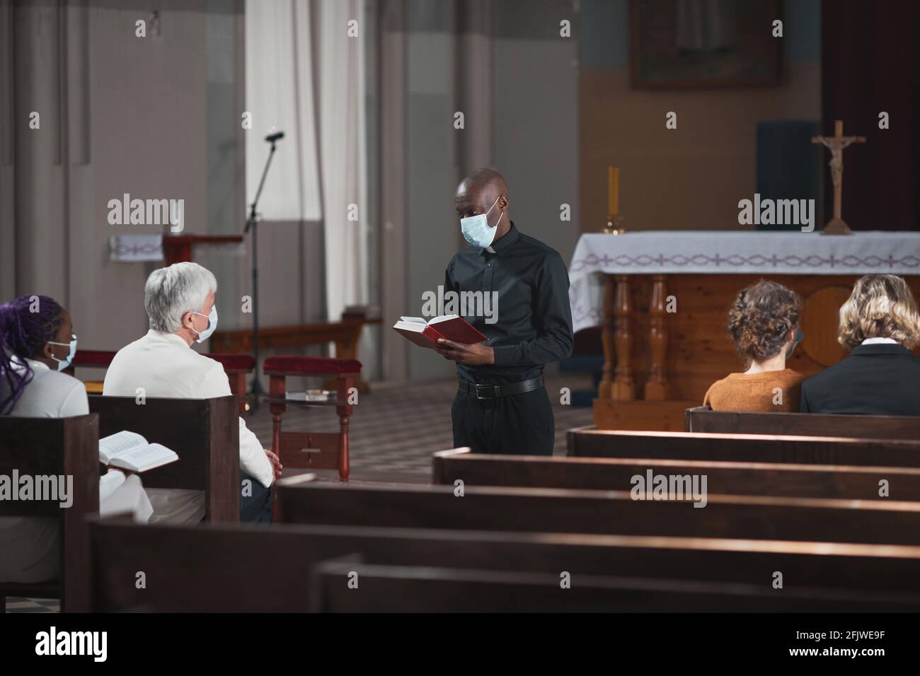 People sitting during Sunday mass in the church and listening to priest ...