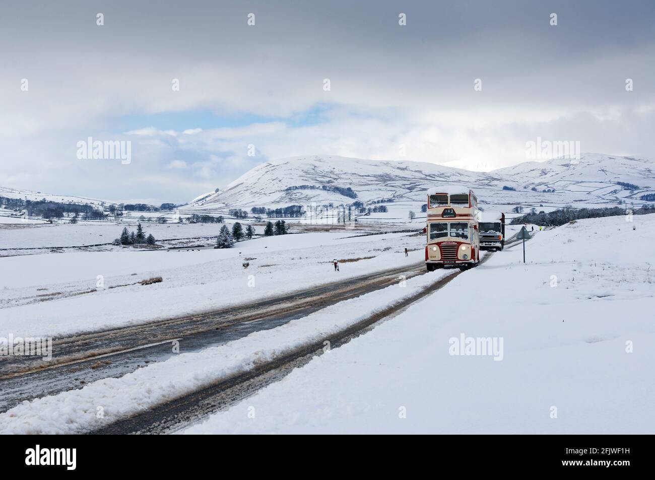 Classic double decker Ribble bus driving along a snowy road in Cumbria ...
