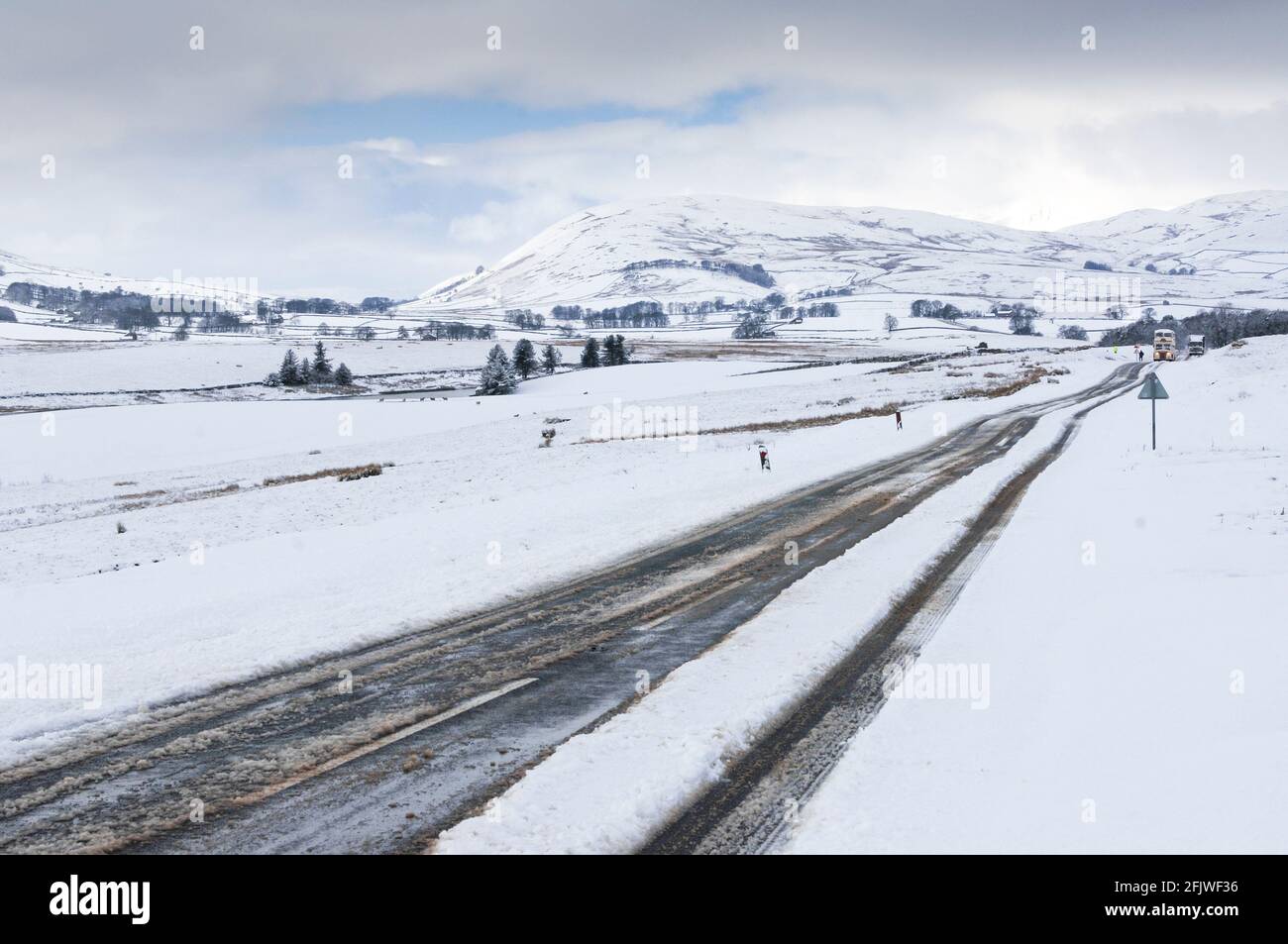 Classic double decker Ribble bus driving along a snowy road in Cumbria ...